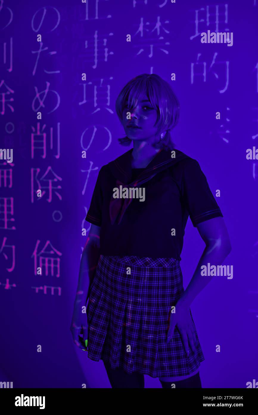 cosplay woman in school uniform standing in blue neon light on backdrop ...