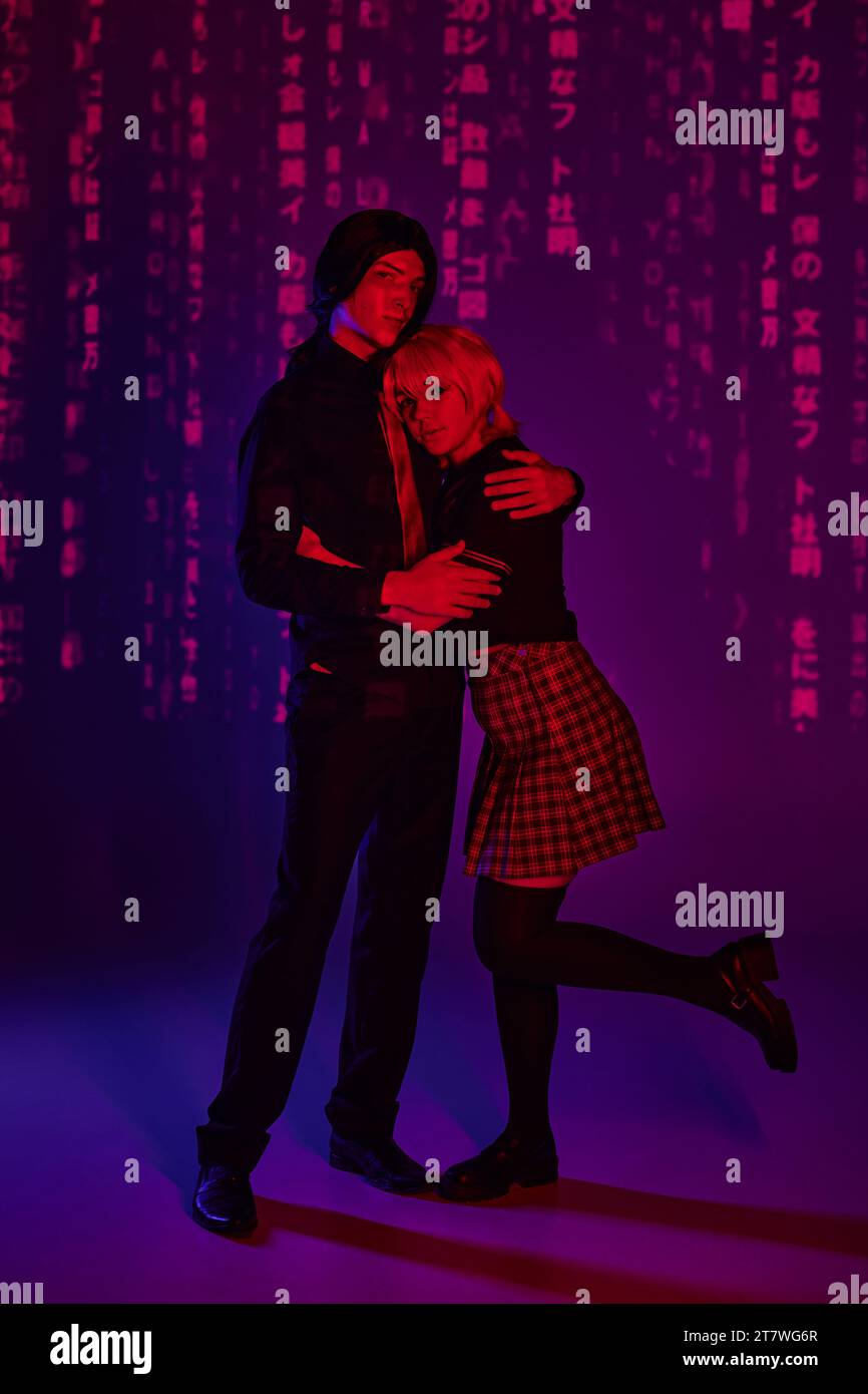 cosplay students in uniform embracing in red neon light on blue and ...