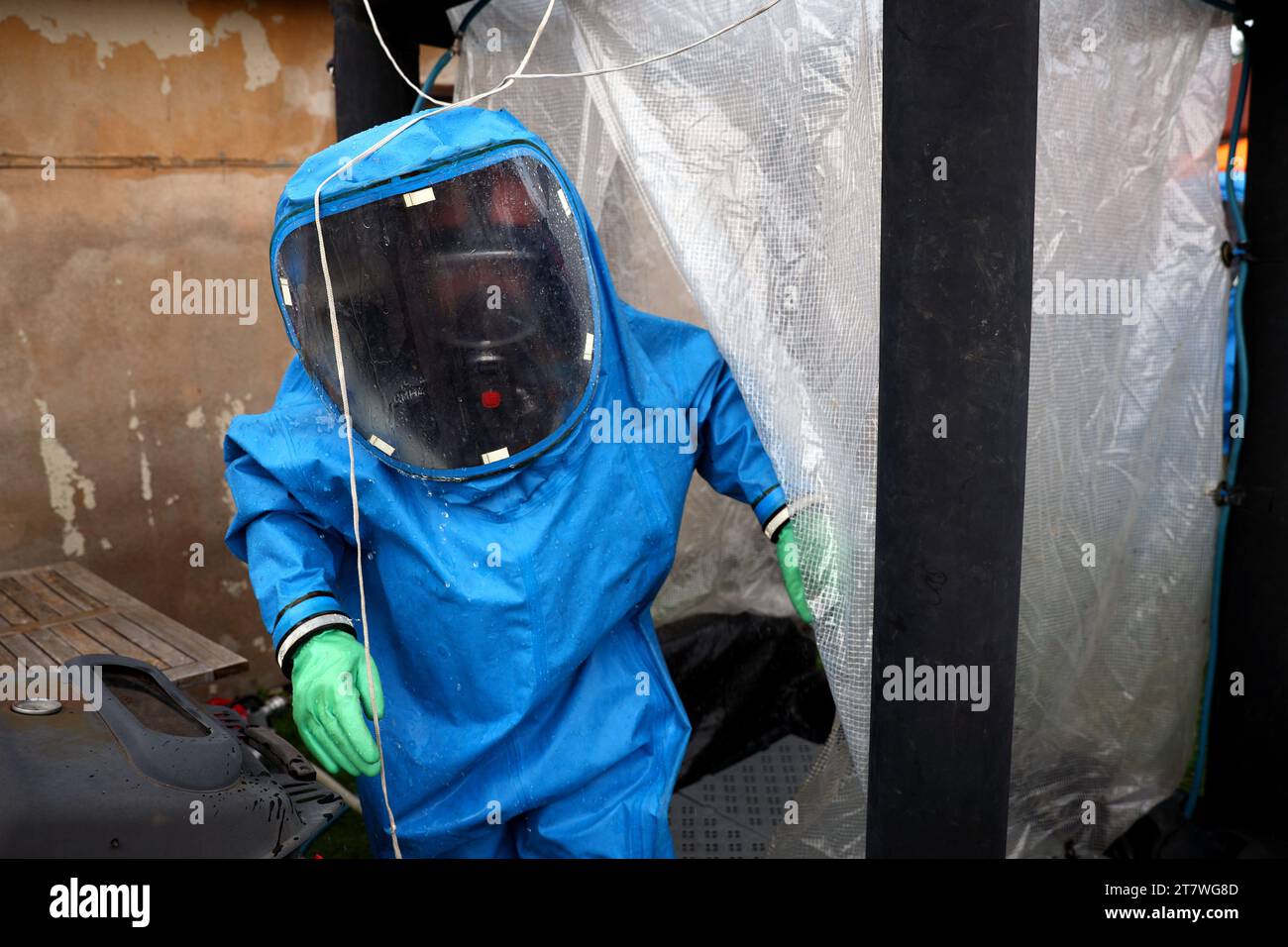 Person wears blue Personal protective equipment (PPE) with gas mask for ...
