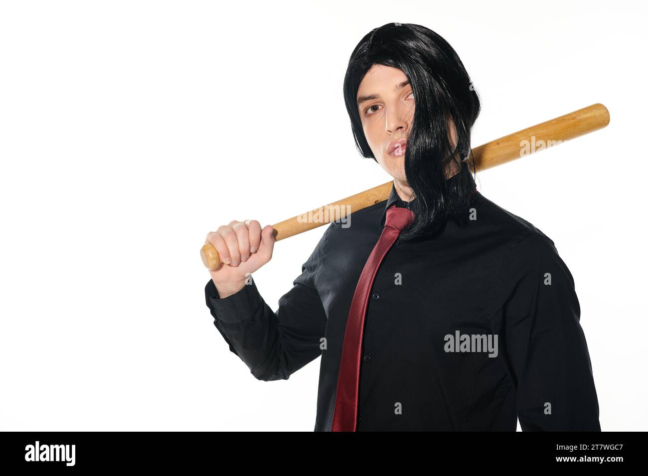 young man in black wig and red tie holding baseball bat and looking at ...