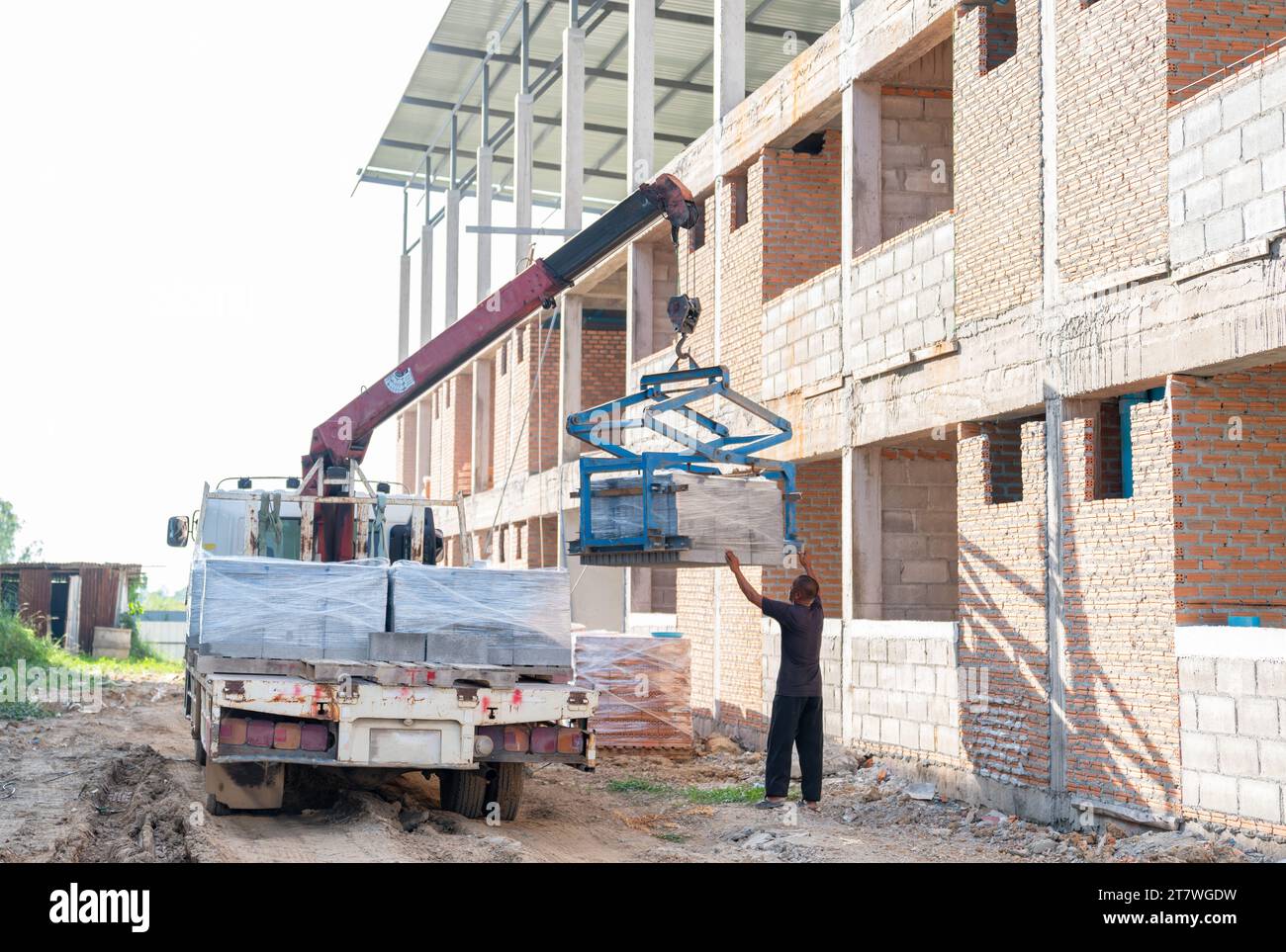 Workers are helping mobile crane to manage concrete block for assembly ...