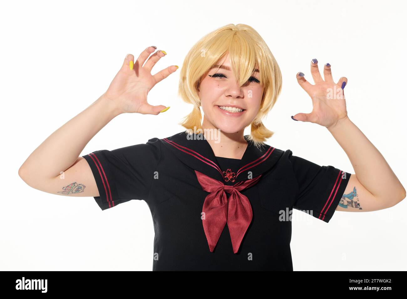 cheerful tattooed woman in school uniform showing frightening gesture ...