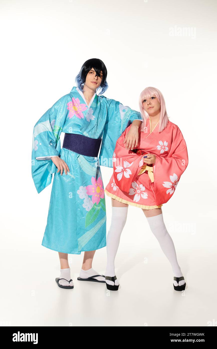 full length of young and vibrant couple in kimonos and wigs on white ...