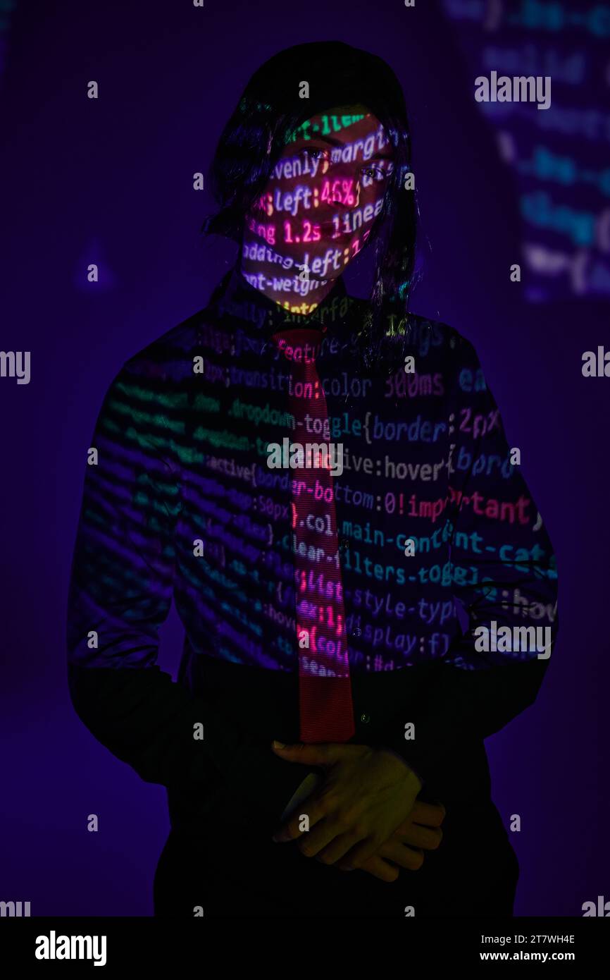 young student in uniform in neon light with programming symbols on dark ...
