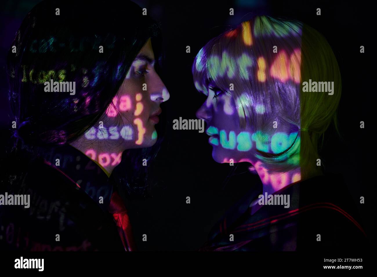 side view of young students with neon programming lettering on dark ...