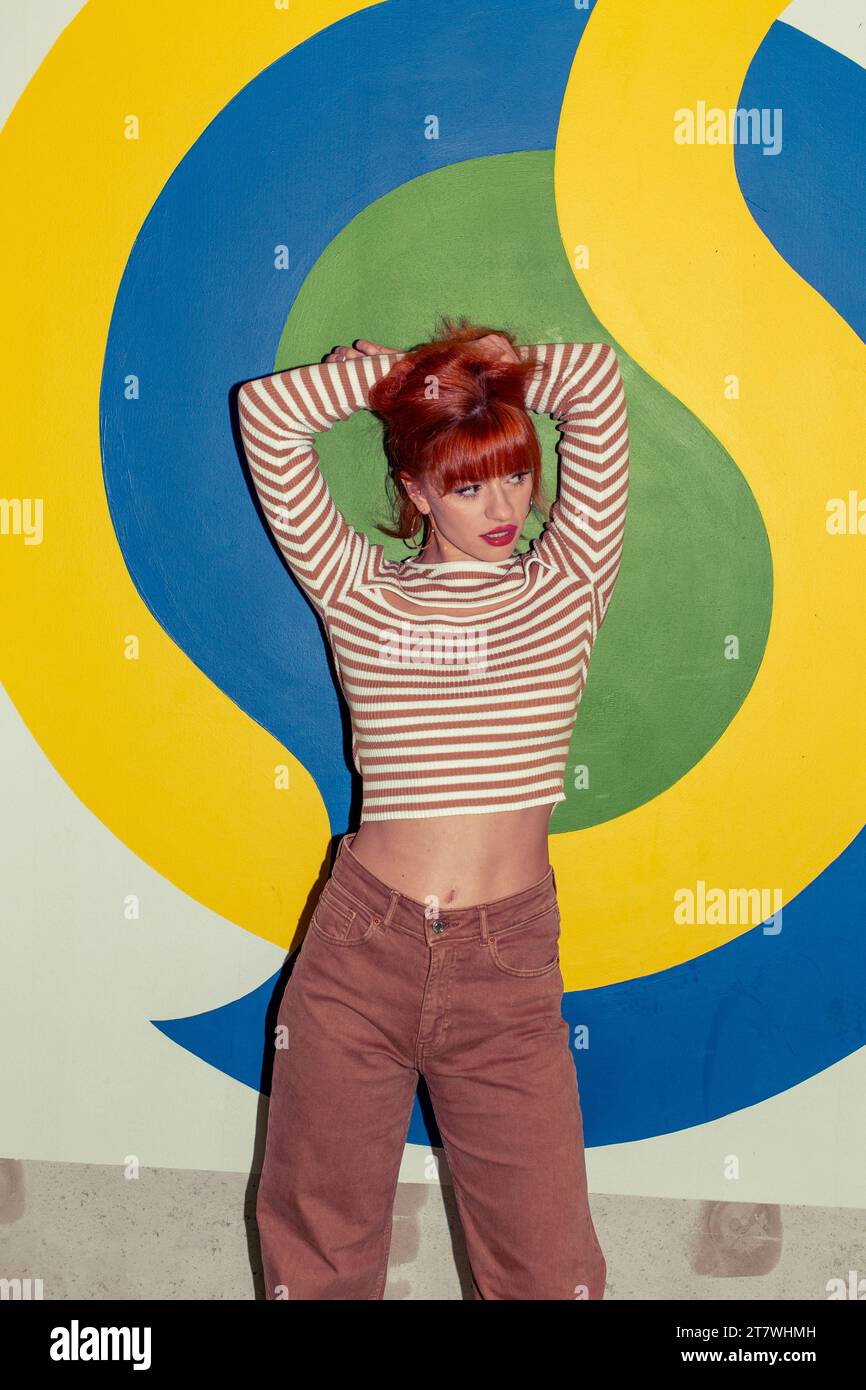 Young redhead Caucasian woman in retro style of 70s posing at colorful ...