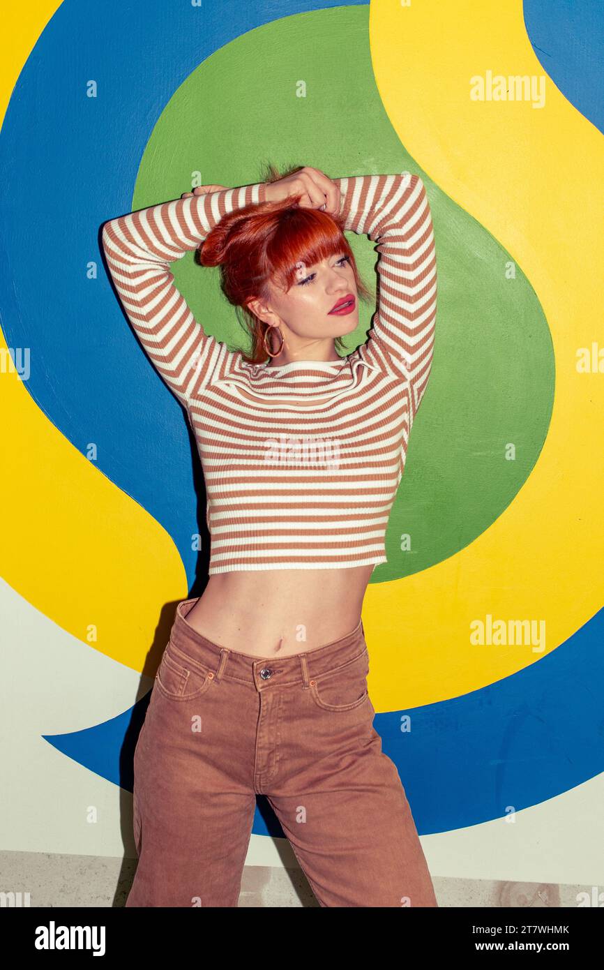 Young redhead Caucasian woman in retro style of 70s posing at colorful ...