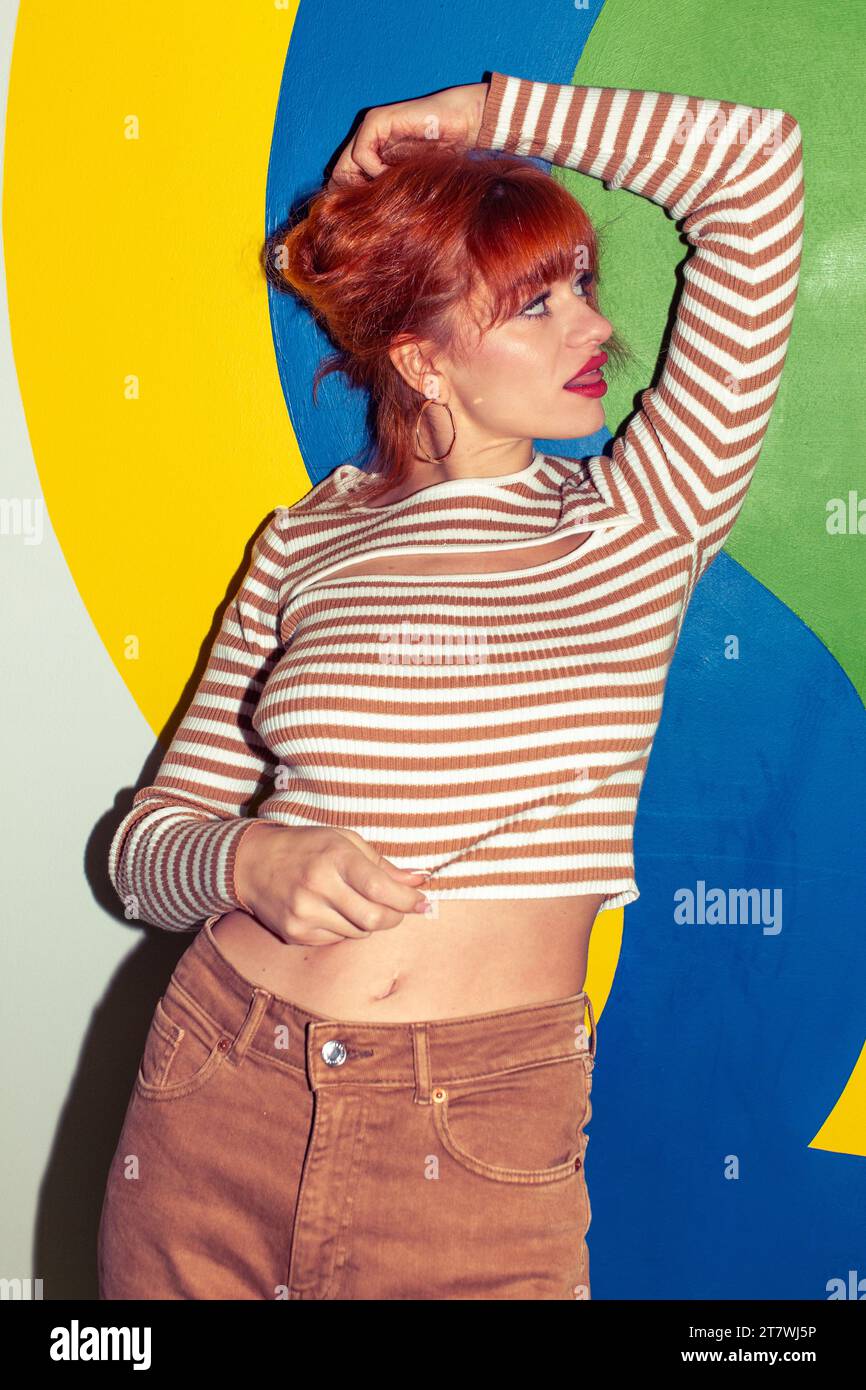 Young redhead Caucasian woman in retro style of 70s posing at colorful ...