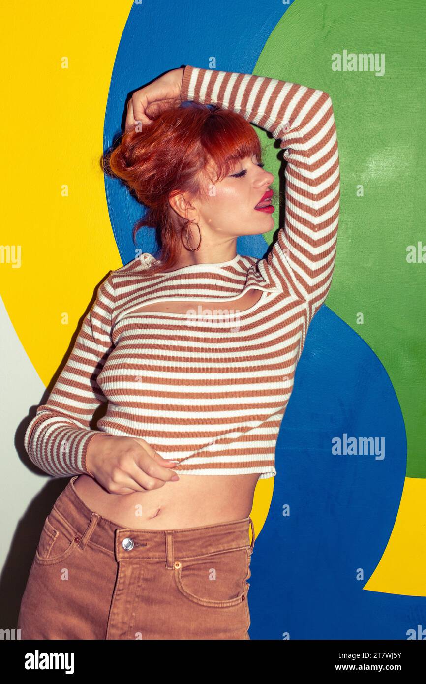 Young redhead Caucasian woman in retro style of 70s posing at colorful ...