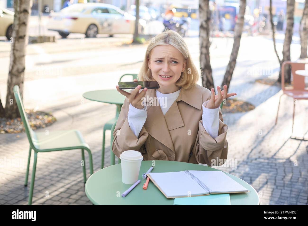 Portrait of young urban female model, sitting in cafe outdoors ...