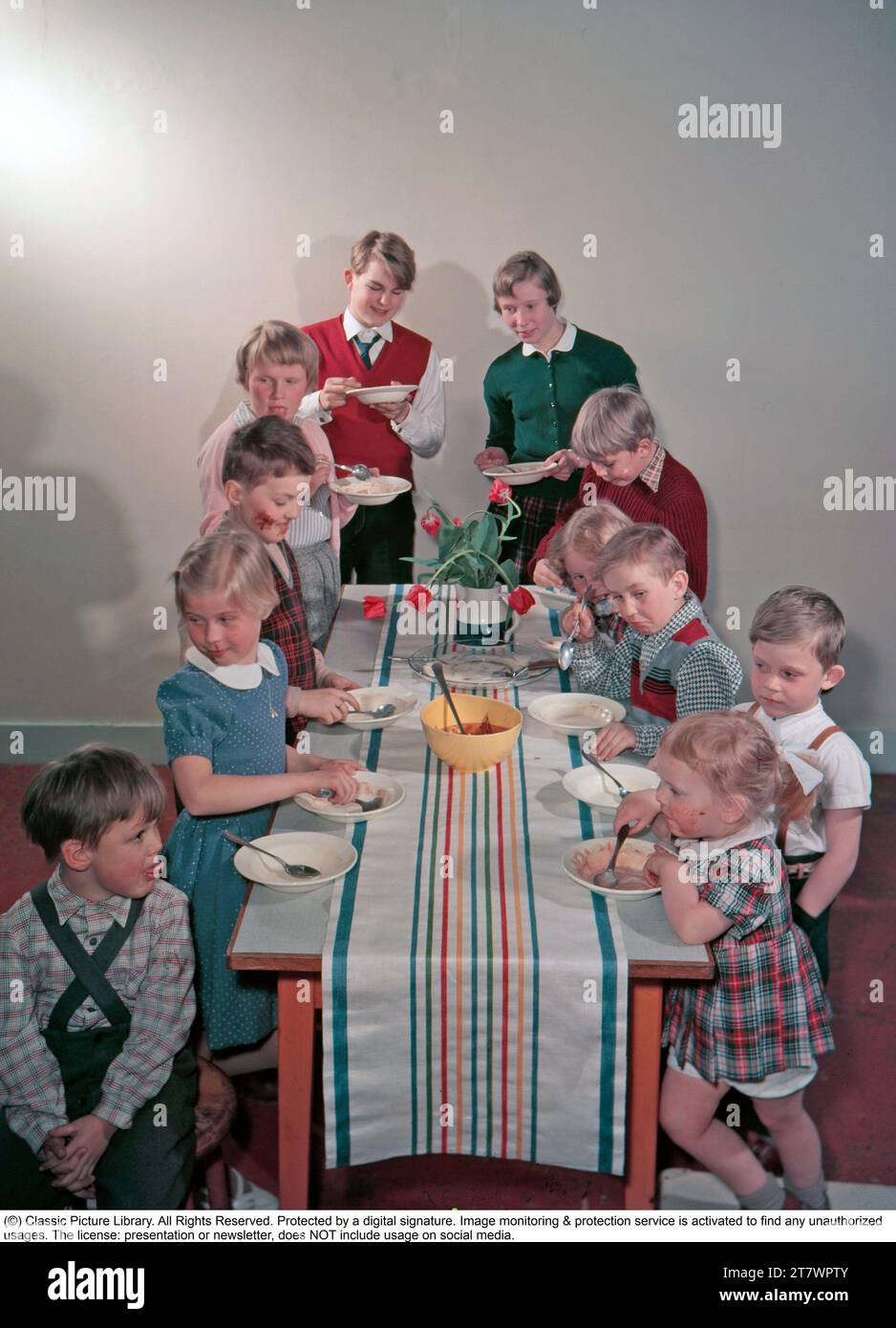 Children in the 1950s. Girls and boys are sitting a table together ...