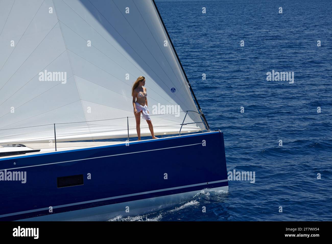 Aerial photo of a girl in a bikini standing on the foredeck of a 50ft sailing yacht underway ...