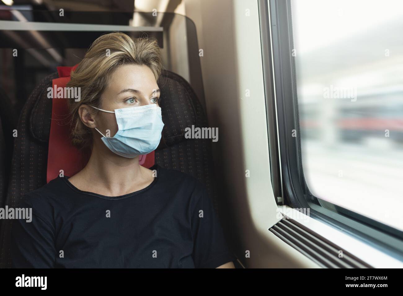 Young woman wearing medical face mask riding a train during her journey ...