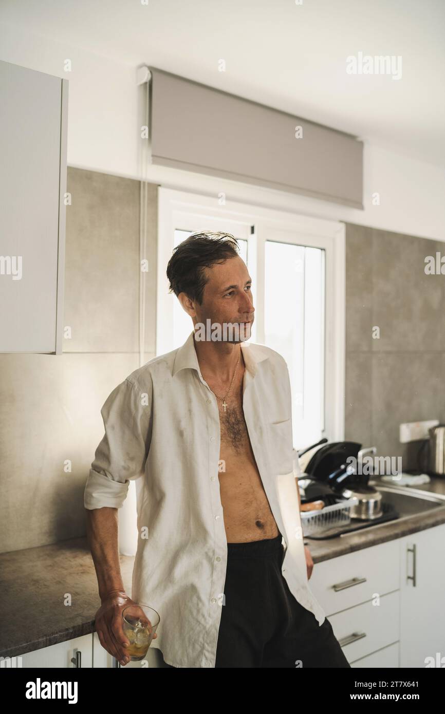 Attractive male slob drinking whiskey in his kitchen Stock Photo - Alamy