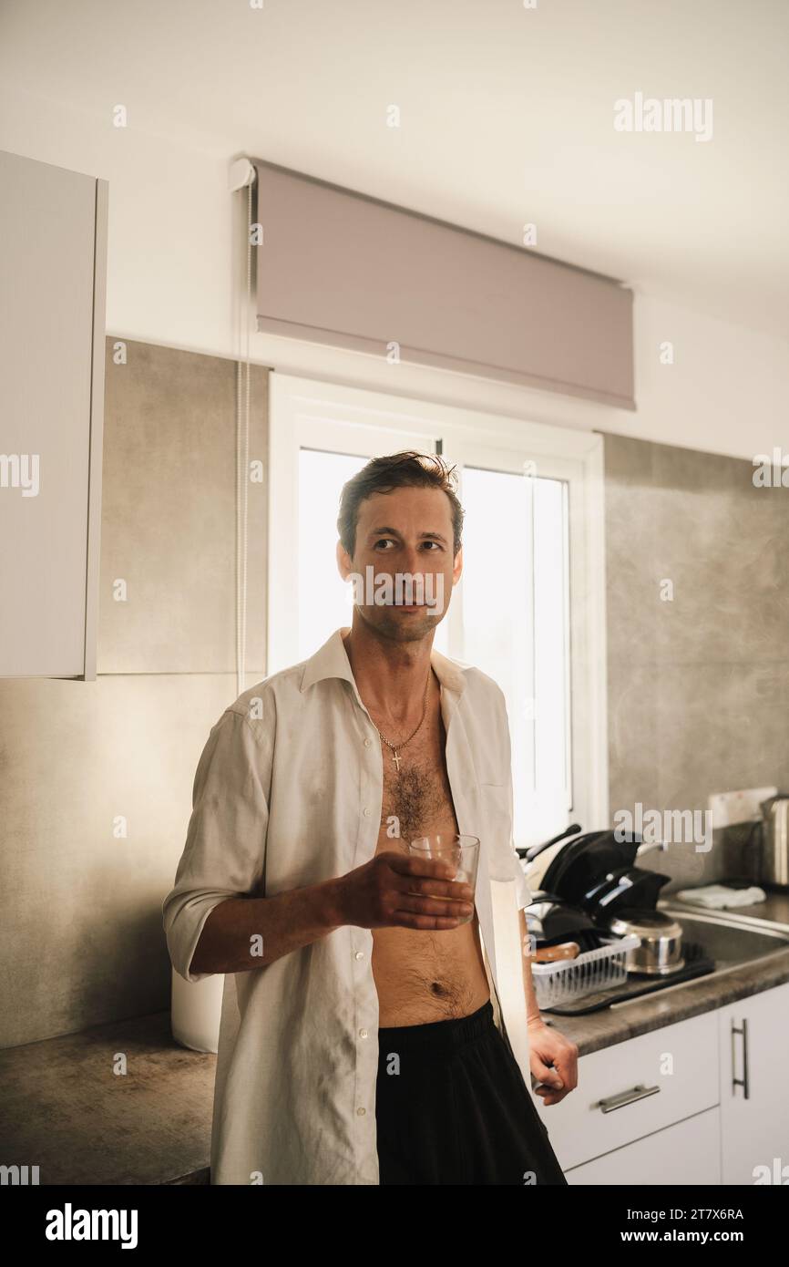 Attractive male slob drinking whiskey in his kitchen Stock Photo - Alamy