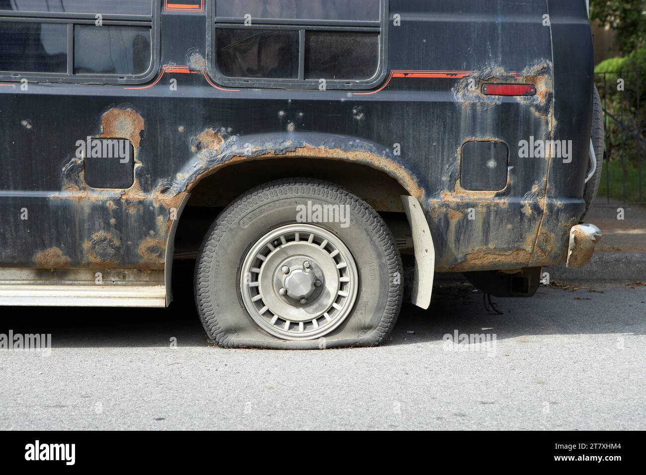 Old rusted van parked at curb with flat tire Stock Photo - Alamy