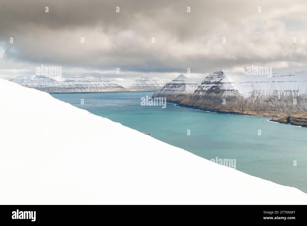 Snow-covered cliffs and mountains along Funningur fjord, Eysturoy ...