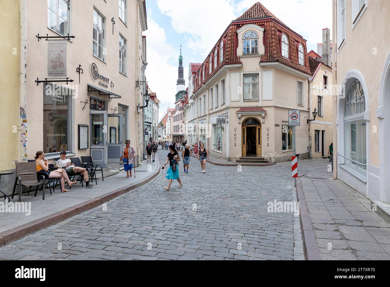 Tourists and locals walking on cobbled street, exploring old part of ...