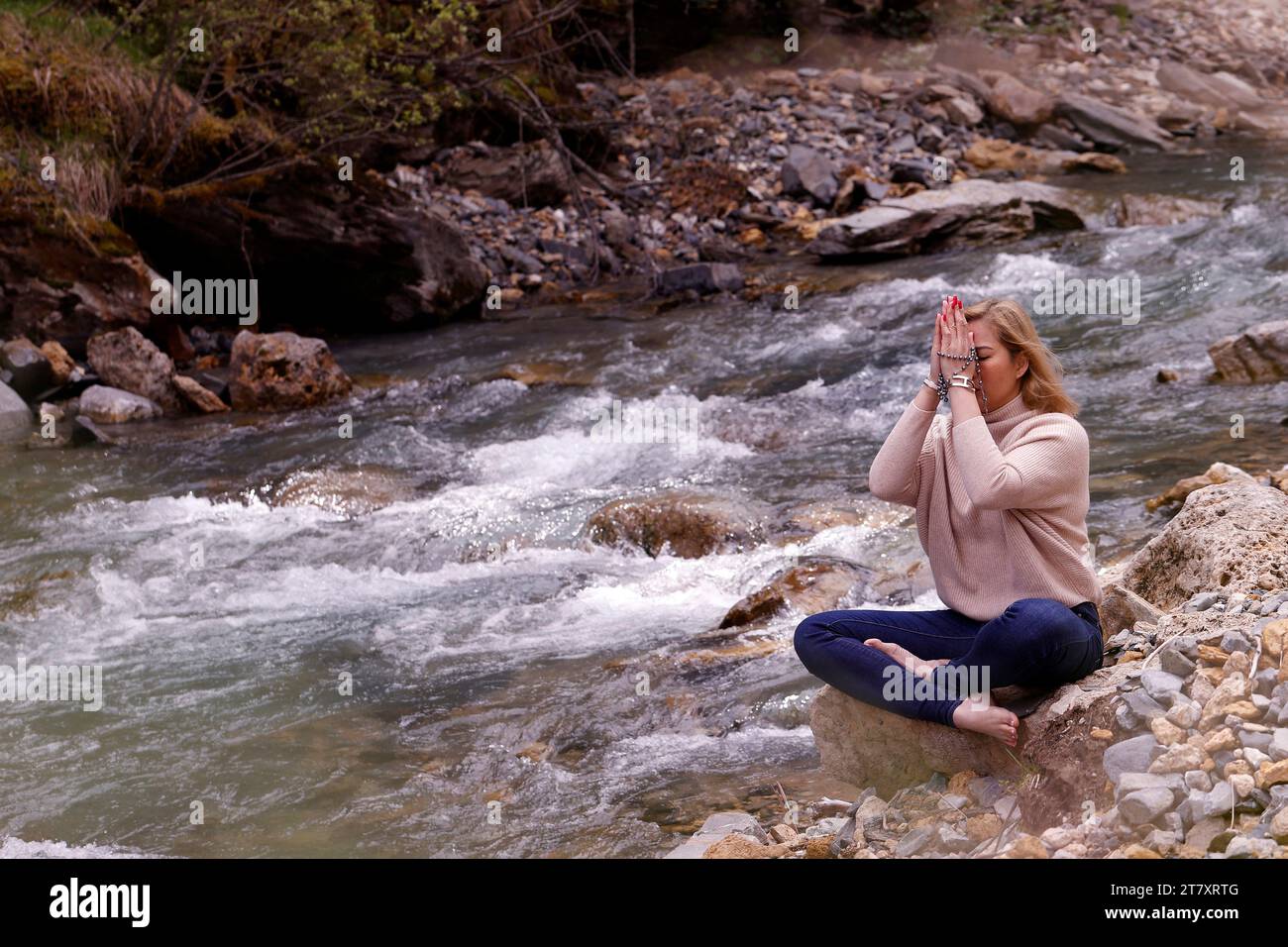 Praying woman sitting on a rock at the edge of a river, concept of ...