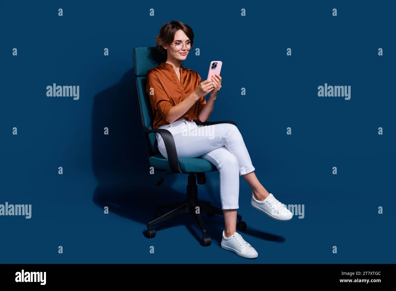 Full size photo of pretty young girl sit armchair hold device dressed ...