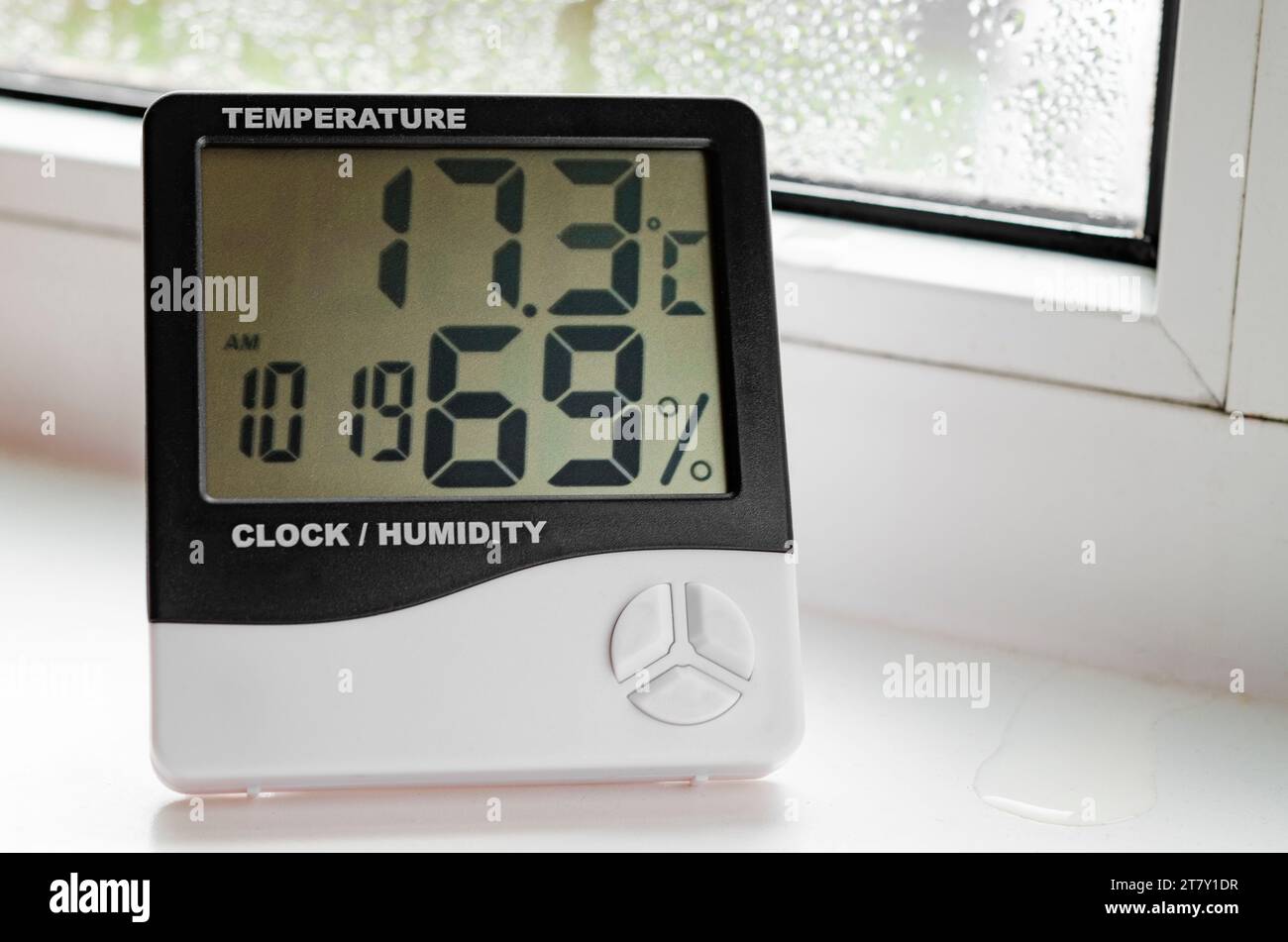 A hygrometer with a thermometer stands on the windowsill with ...