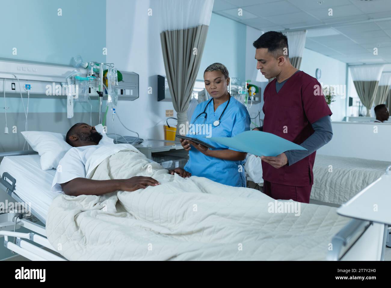 Diverse doctors and male patient is lying in bed talking in hospital ...