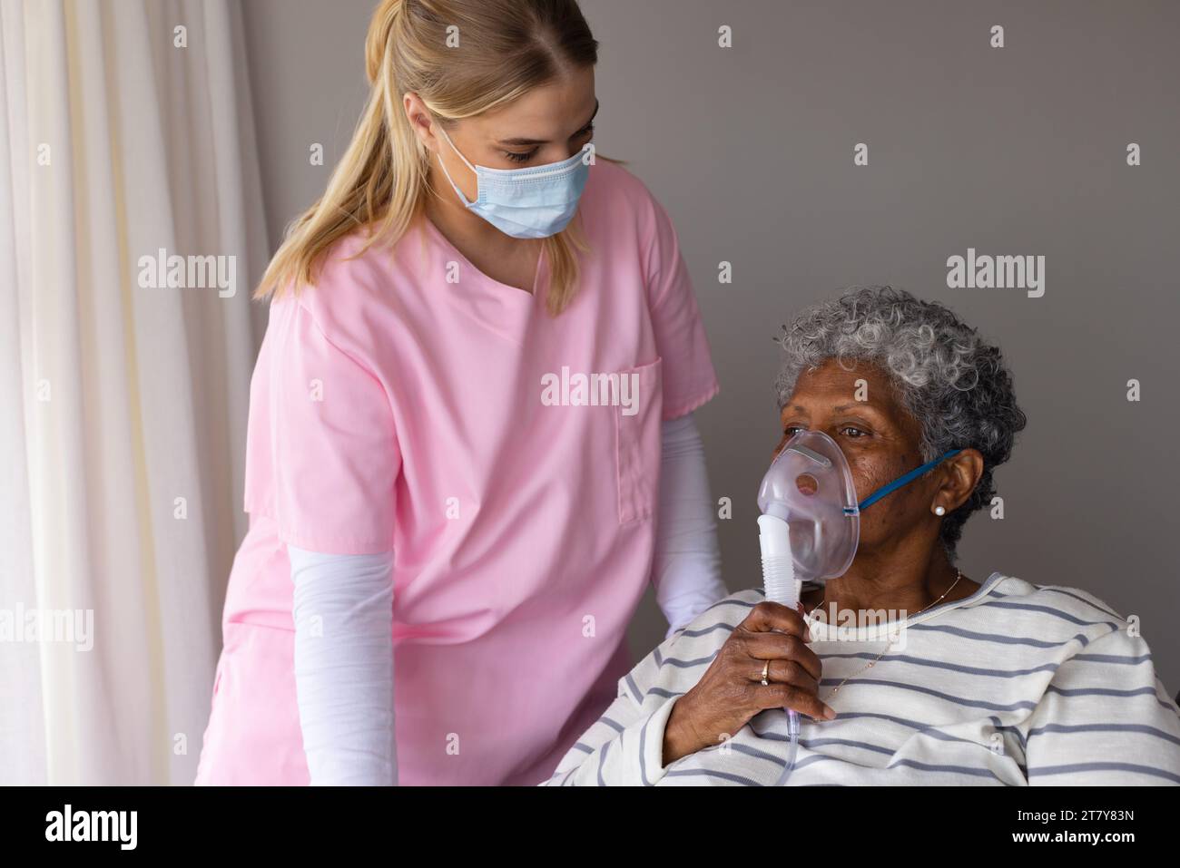 Caucasian female nurse in face mask and senior african american female ...