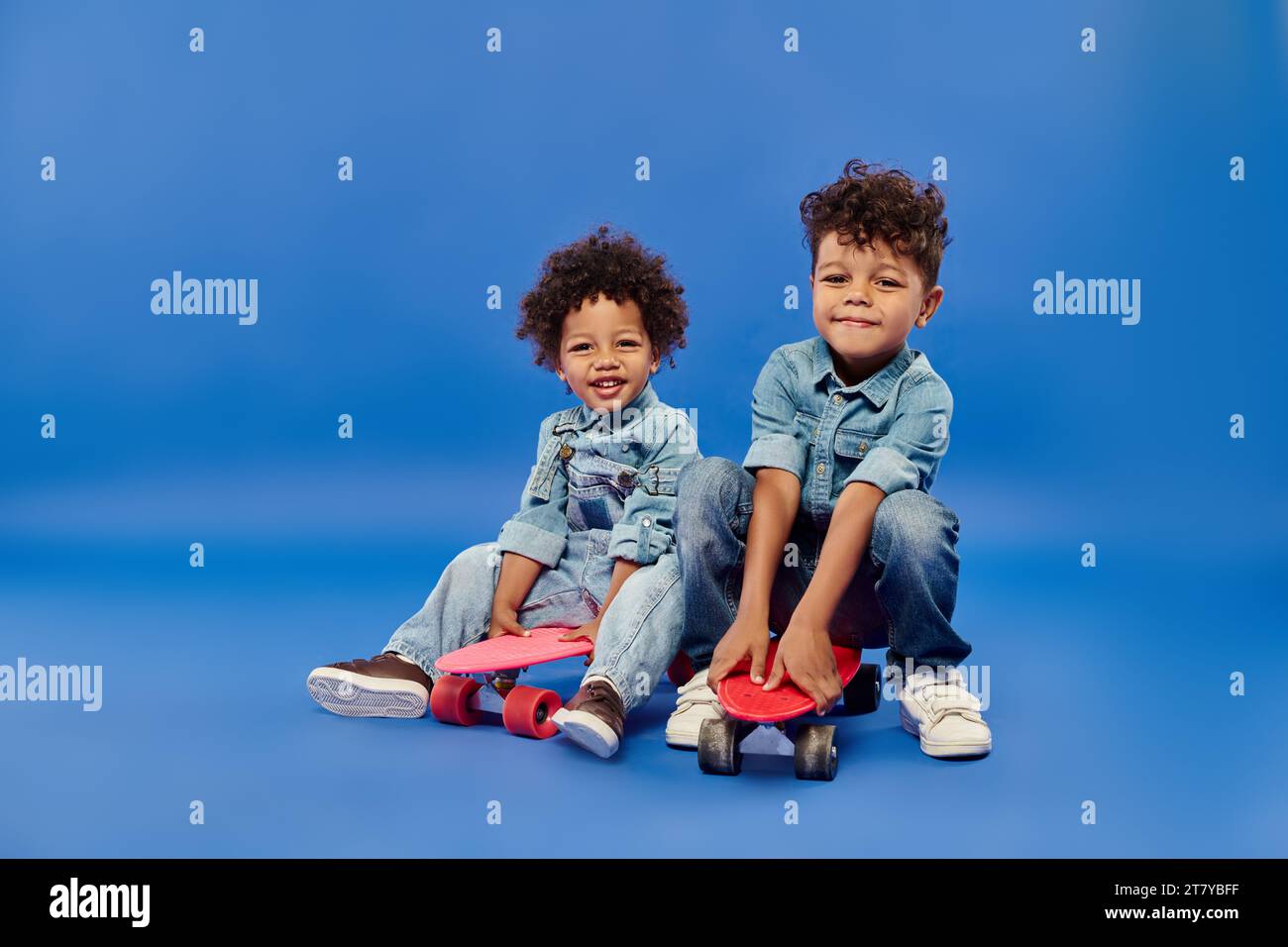 happy african american siblings in stylish denim clothes sitting on ...