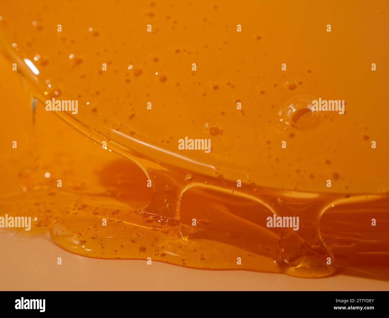 Liquid shower gel flows gracefully across a bright orange background ...