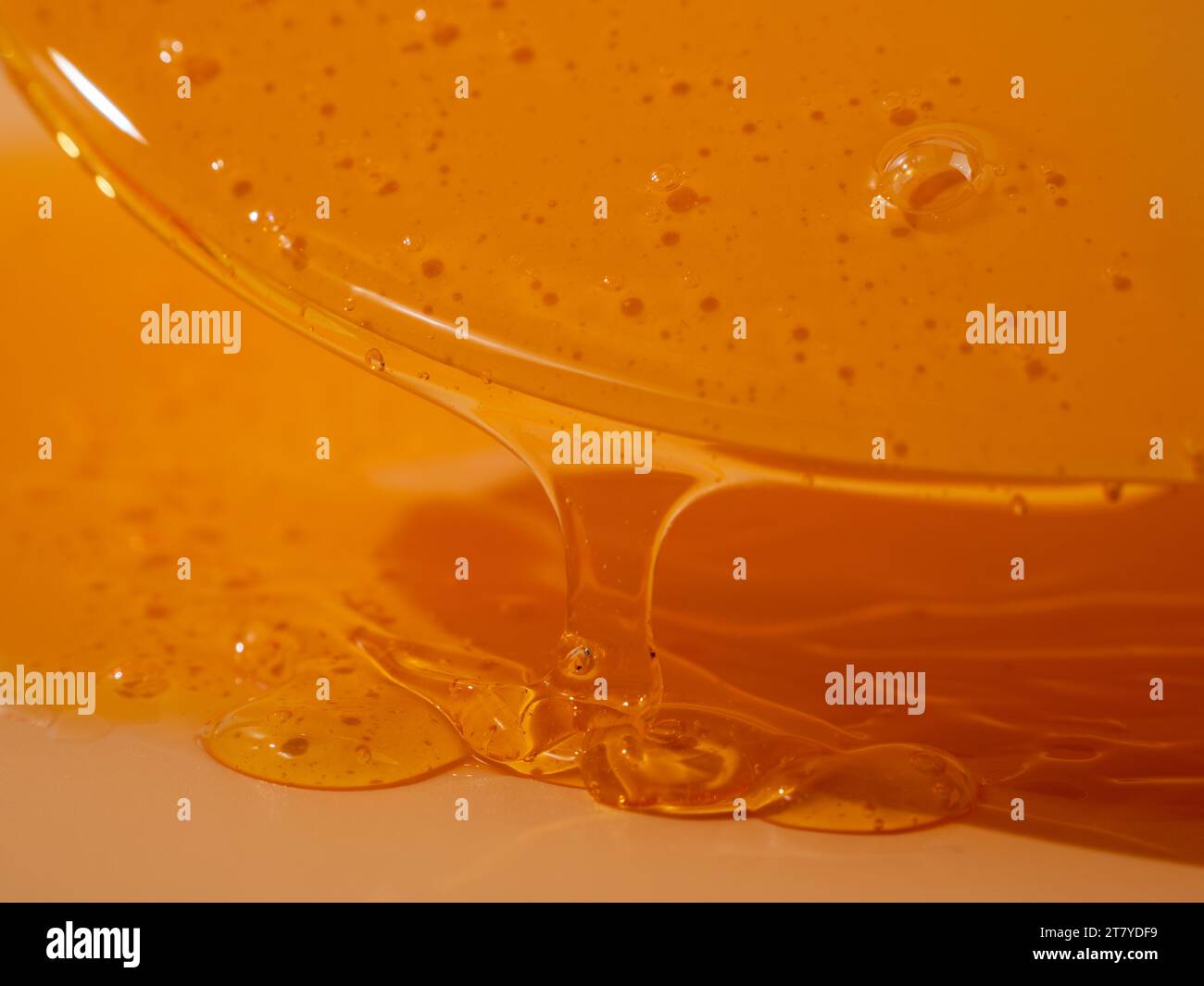 Liquid shower gel flows gracefully across a bright orange background ...