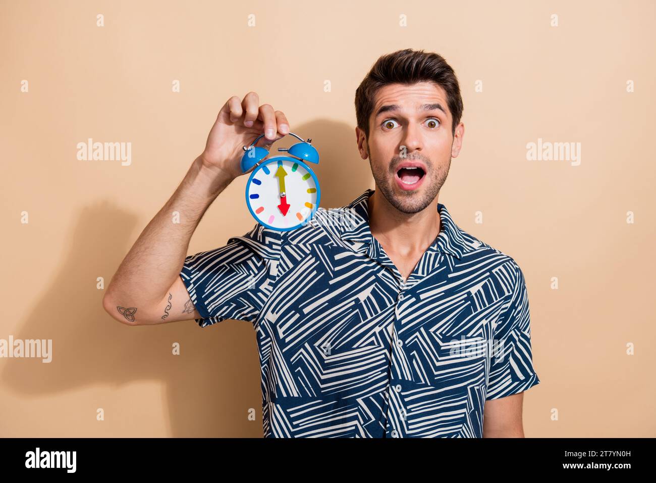 Photo of young impressed guy confused reaction hold miniature toy timer ...