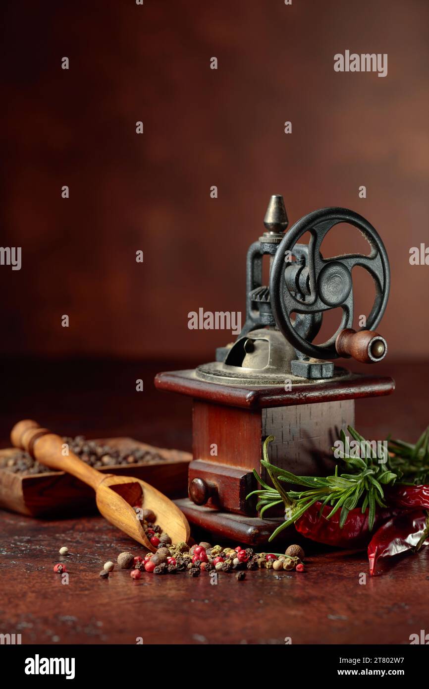 Old pepper mill with cooking utensils, spices and rosemary on a brown ...