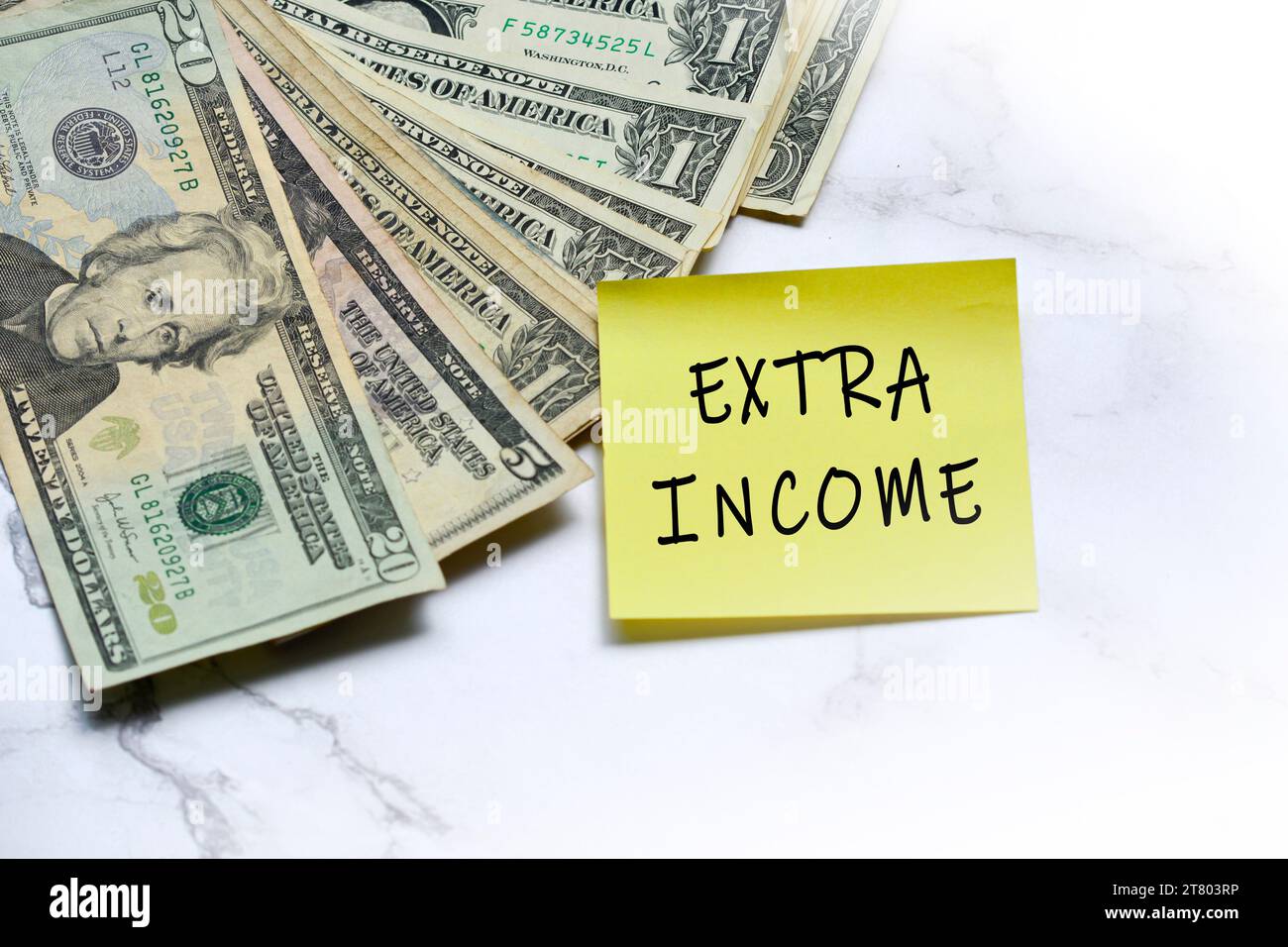 Dollars bill and stick note with text written EXTRA INCOME on mable ...