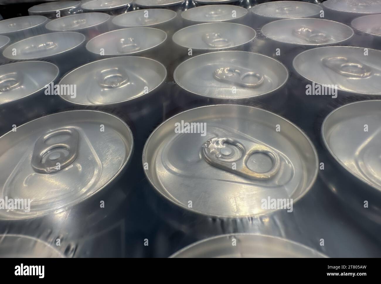 Aluminum drink cans in rows are wrapped in clear plastic and viewed ...