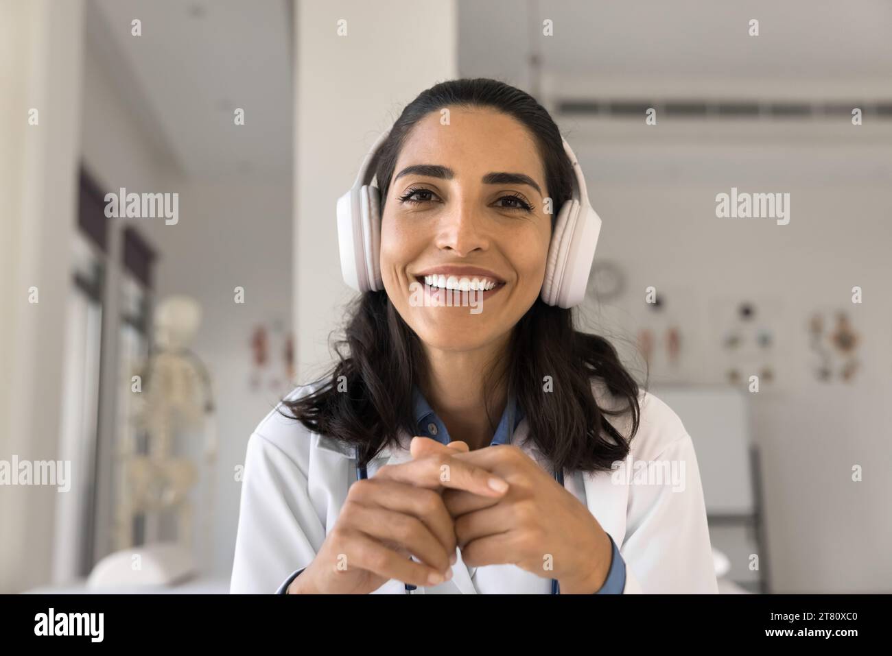Happy beautiful Latin doctor woman in headphones head shot portrait ...