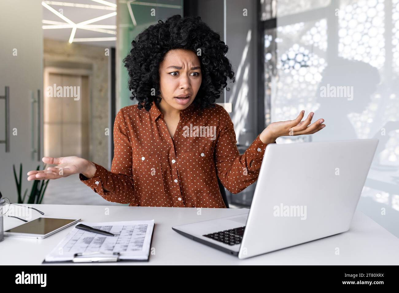 Dissatisfied and disappointed sad woman at workplace looking at laptop ...