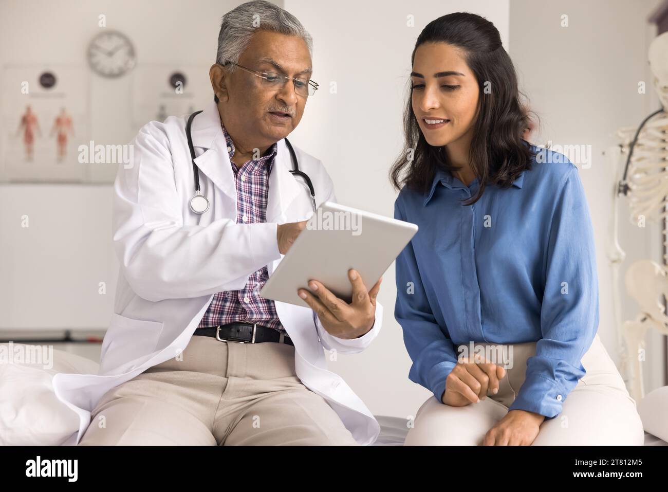 Focused diverse senior doctor and young patient looking at tablet Stock ...