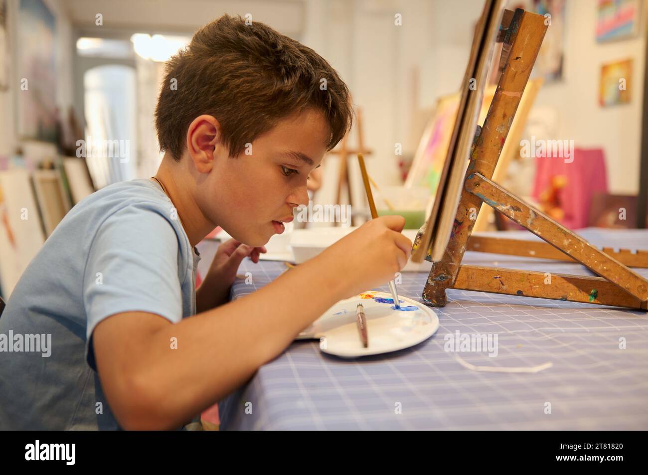 Handsome teenage, schoolboy artist painting on canvas, drawing with ...