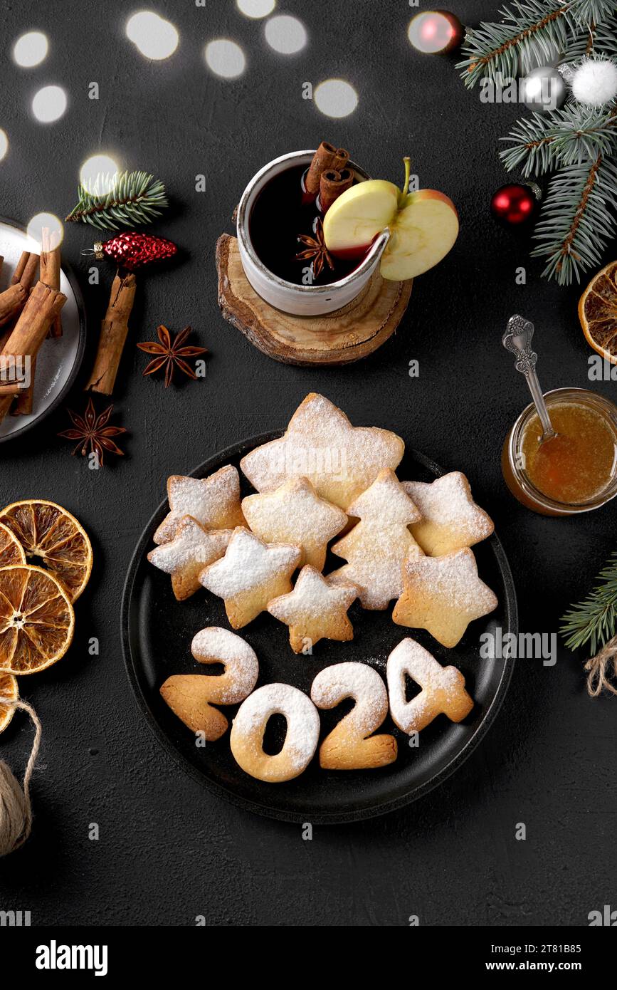 Cookies in the form of numbers 2024 and stars on the dark plate and ...