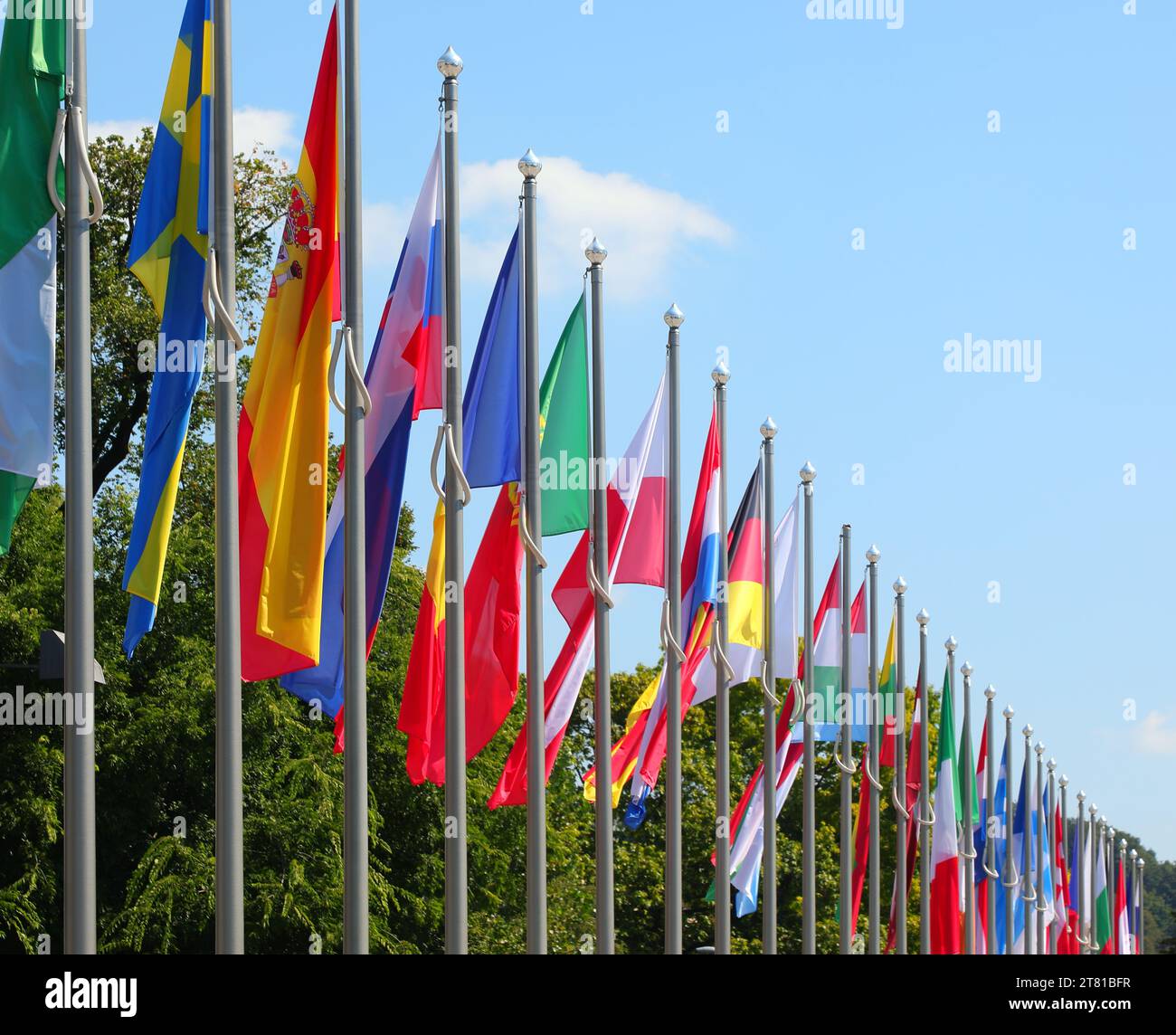 many colorful flags of world states lined up on poles during the ...