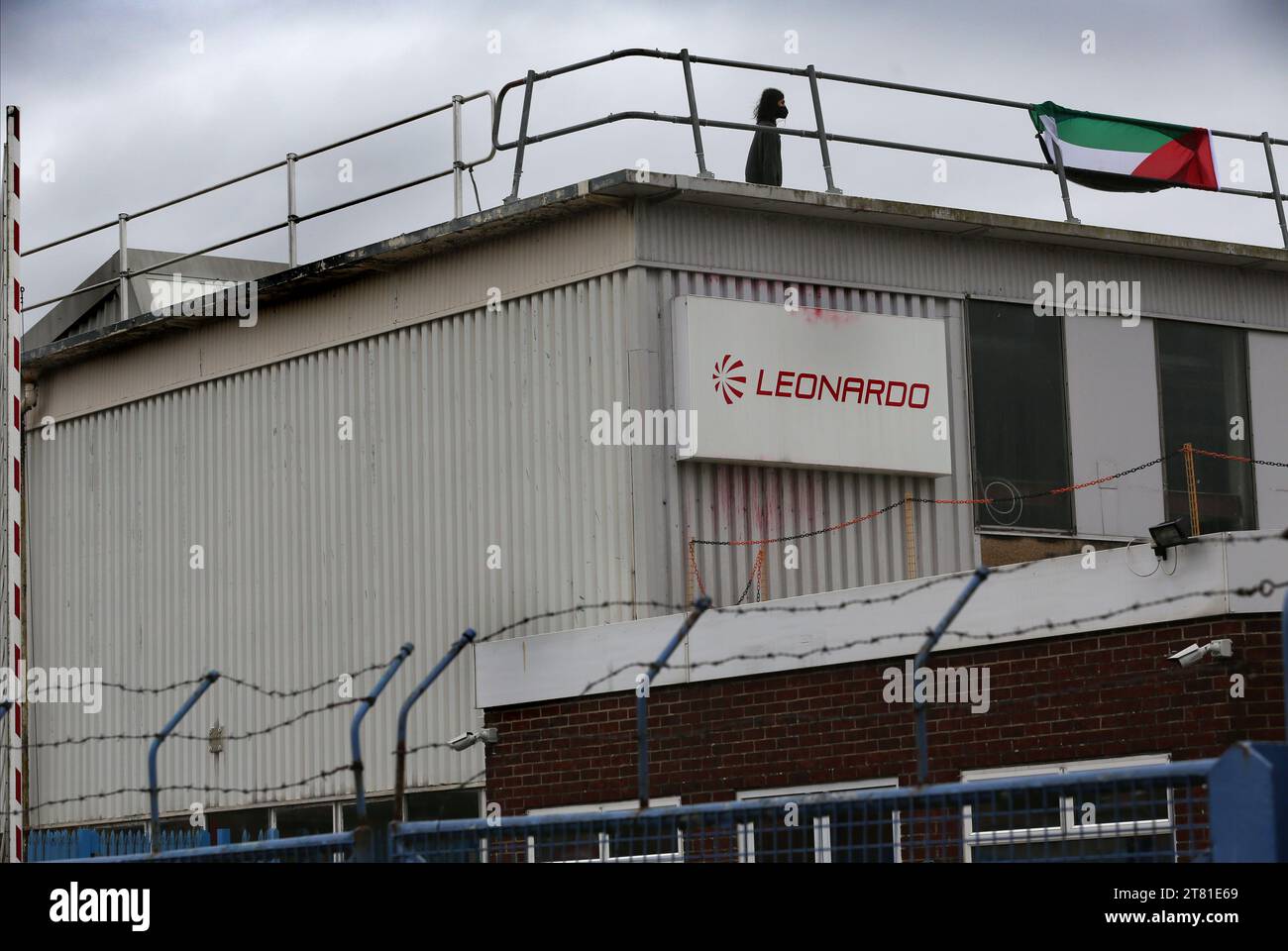 An activist walks on the roof beside a Palestinian flag and the Leonardo factory sign. Palestine ...