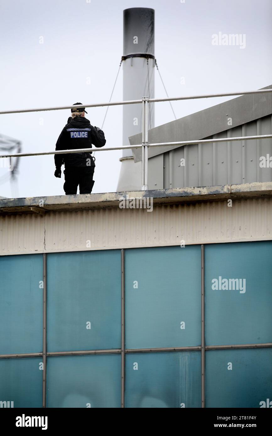 A police officer stands-by on the roof as emergency services clear the ...