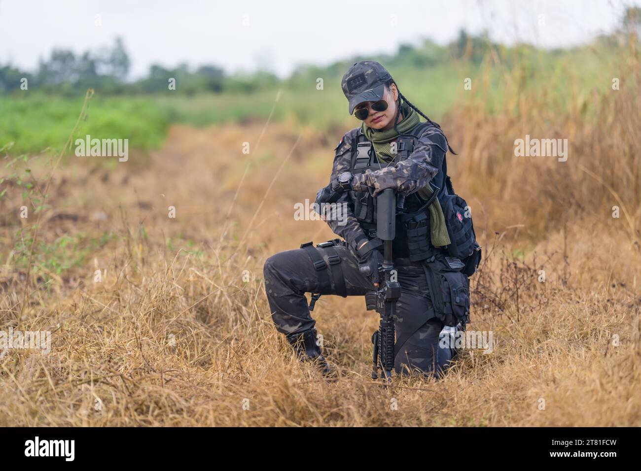 A male adult in a camouflage outfit is seated while cradling a rifle ...