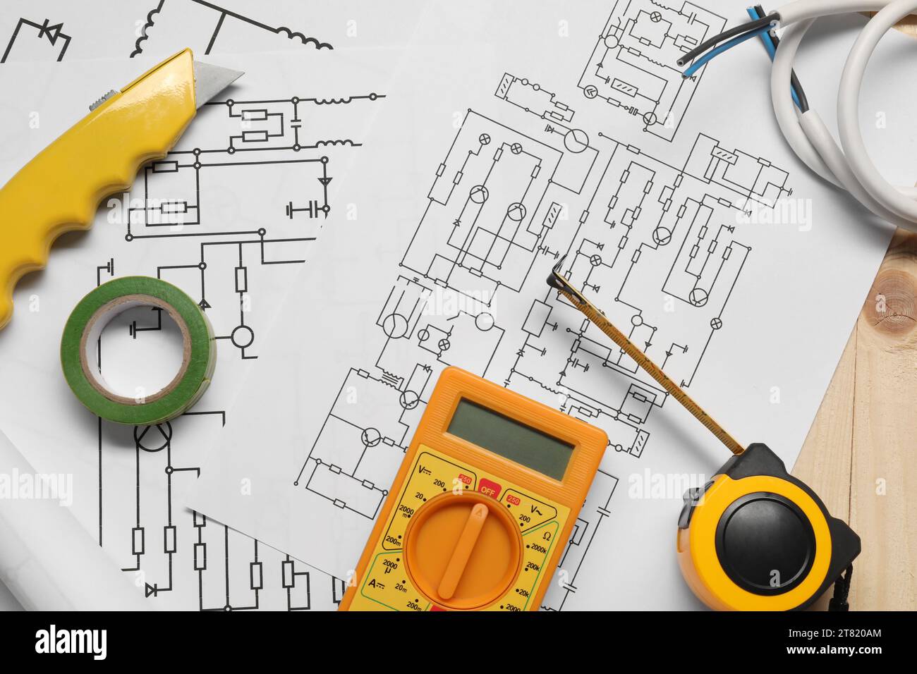 Wiring diagrams, wires and digital multimeter on wooden table, top view ...
