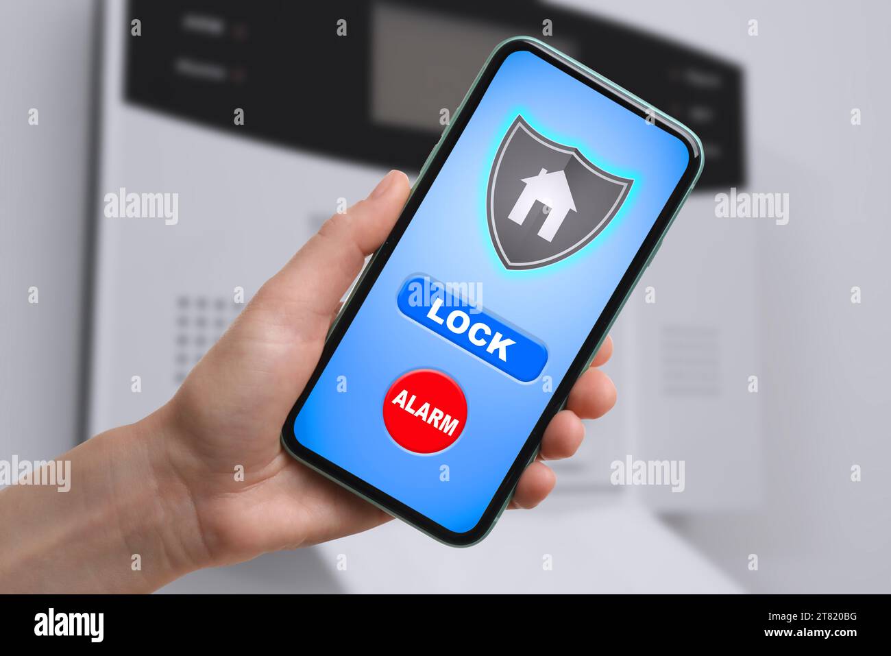 Woman operating home alarm system via mobile phone against white wall ...