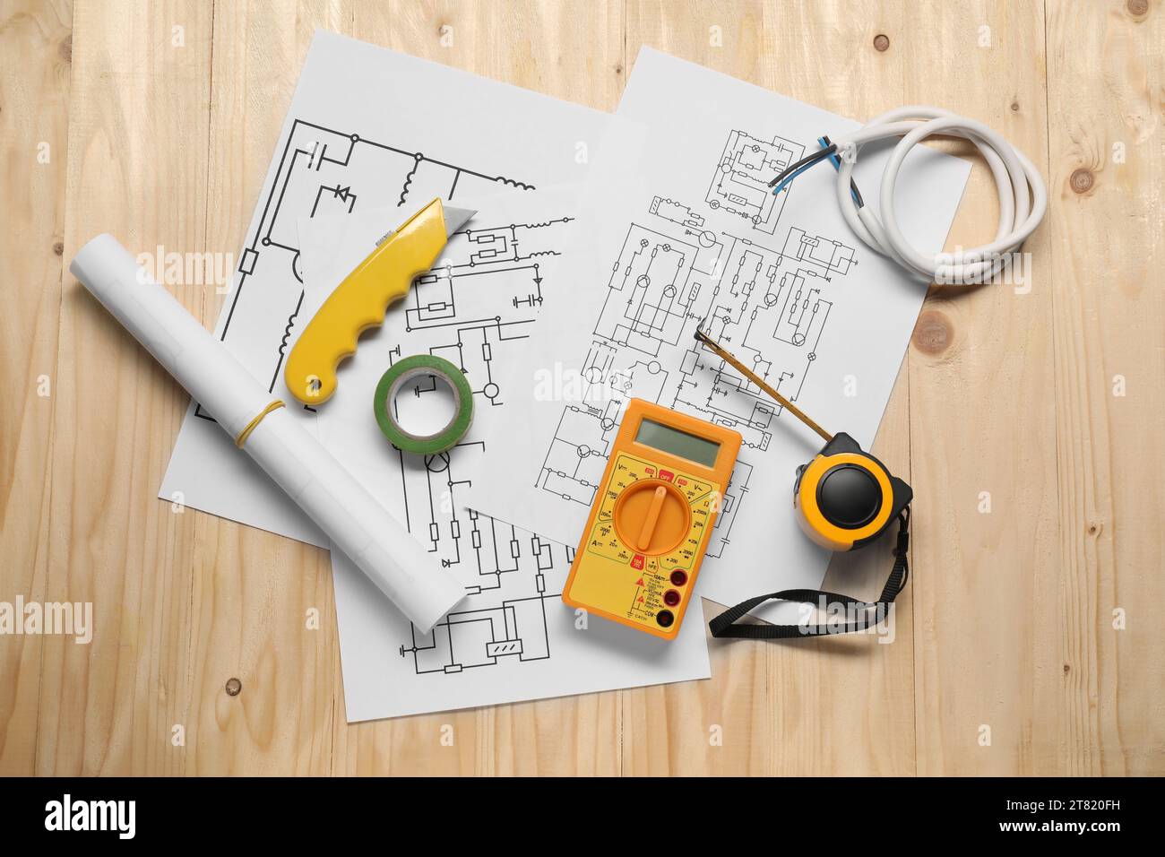Wiring diagrams, wires and digital multimeter on wooden table, flat lay ...
