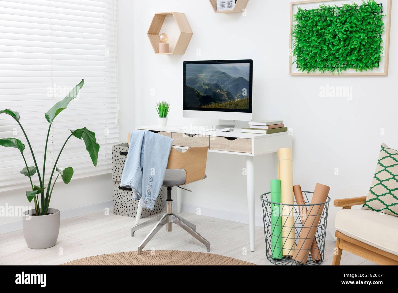 Green artificial plant wall panel and desk with computer in light room ...