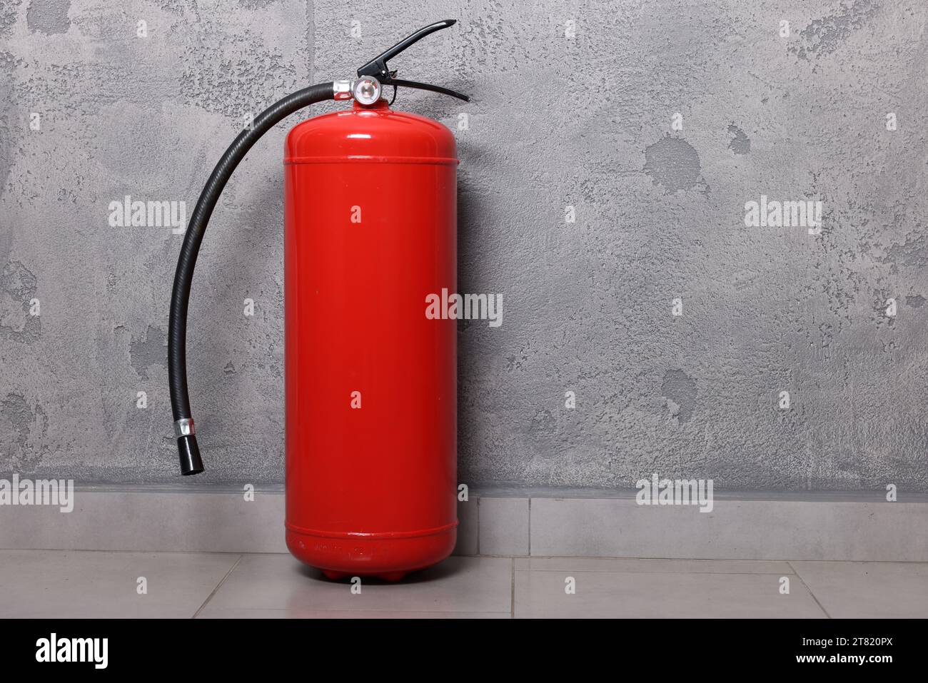 Red fire extinguisher near grey wall, space for text Stock Photo - Alamy