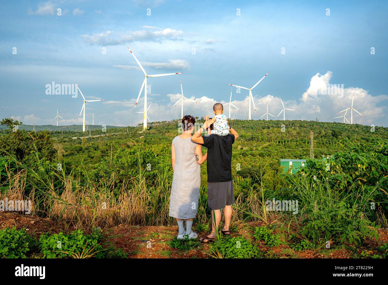 A happy young family looks at wind turbines. Wind turbines are ...
