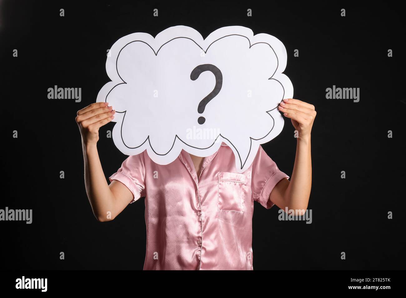 Young woman in pajamas holding speech bubble with question mark on ...